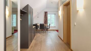 Quarto moderno e bem iluminado com área de refeições, piso de madeira e uma janela grande com cortinas.