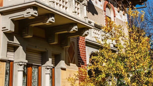 Um edifício com varanda, detalhes arquitetônicos elaborados e fachada de tijolos.