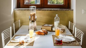Mesa de café da manhã com vista para uma aldeia através de uma janela, uma garrafa de leite e diversos itens de café.