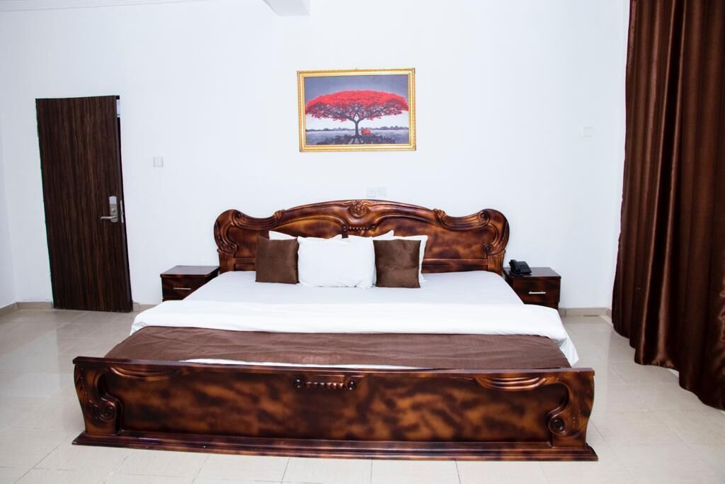 Uma cama de madeira grande com cabeceira, duas mesas de cabeceira e um criado-mudo.