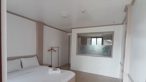 Quarto com uma cama grande, uma mesinha com abajur e janela com vista para o exterior.