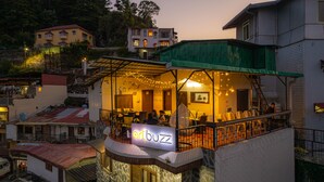 Um restaurante com mesas ao ar livre, uma placa com a inscrição 'artbuzz' e vista para edifícios próximos.