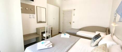 Quarto de hotel com uma cama, uma escrivaninha e uma cadeira.