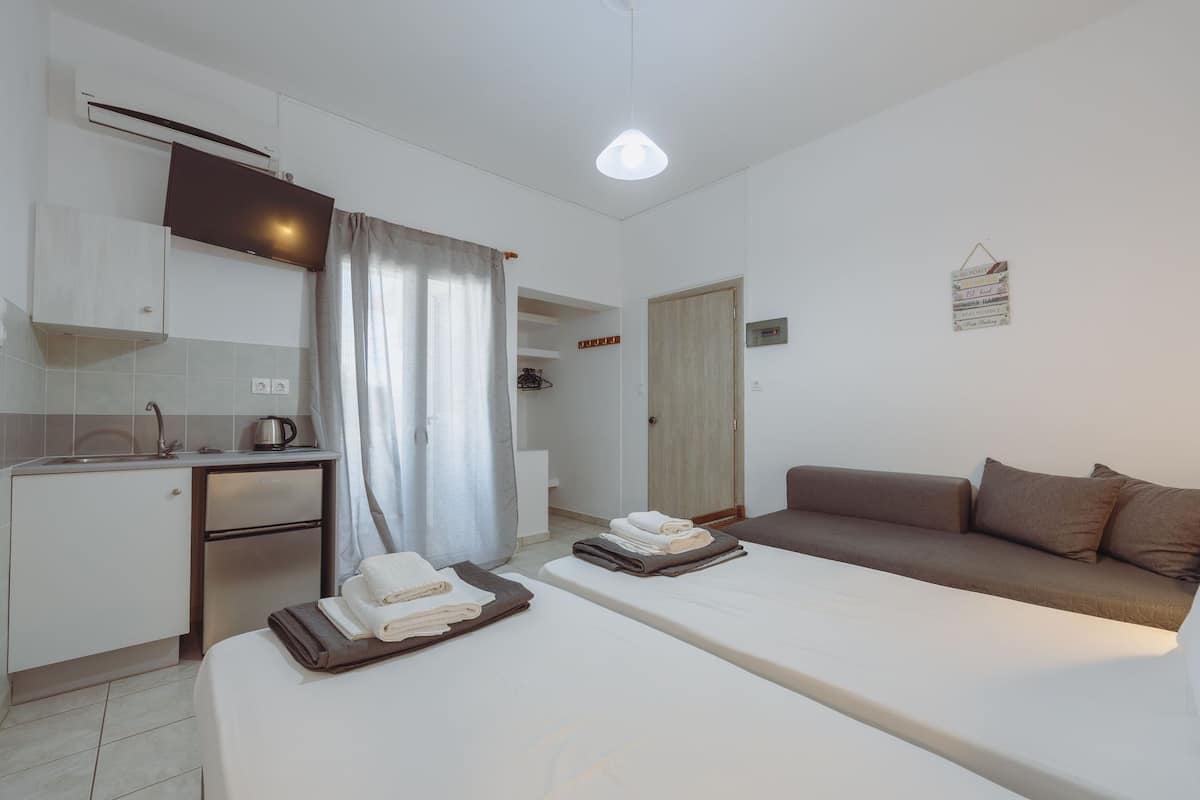 Espaço compacto com cozinha compacta, sofá e cama, com toalhas.