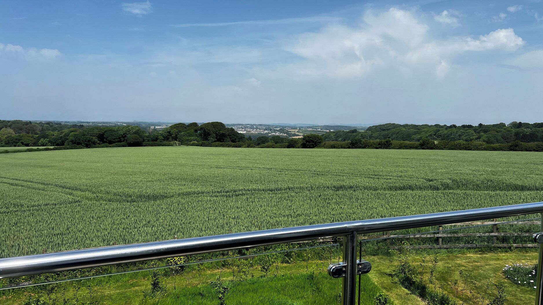 Vista de um campo verde com um guarda-corpo de metal em primeiro plano.