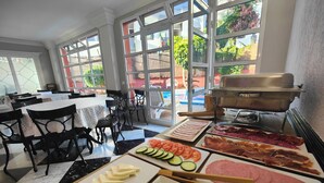Um buffet de café da manhã com diversos queijos, carnes e vegetais.