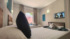 Quarto de hotel com duas camas, televisão de tela plana, um quadro e vista para o exterior.