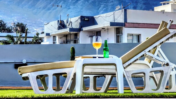 Terraço com vista para a montanha, um copo de vinho e uma garrafa verde.