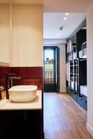 Um banheiro moderno com uma pia grande branca, uma torneira preta e um revestimento de azulejos vermelhos.