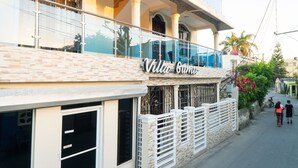 Um hotel com placa de identificação, varanda e portão.