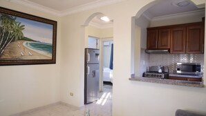 Uma sala de estar ampla com cozinha equipada com eletrodomésticos modernos e armários de madeira.