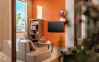 Uma sala de estar moderna com sofá, mesa de centro, estante de livros e uma TV de tela plana fixada na parede.