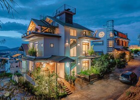 Uma casa moderna de dois andares, com varanda, escadaria e entrada para carros.