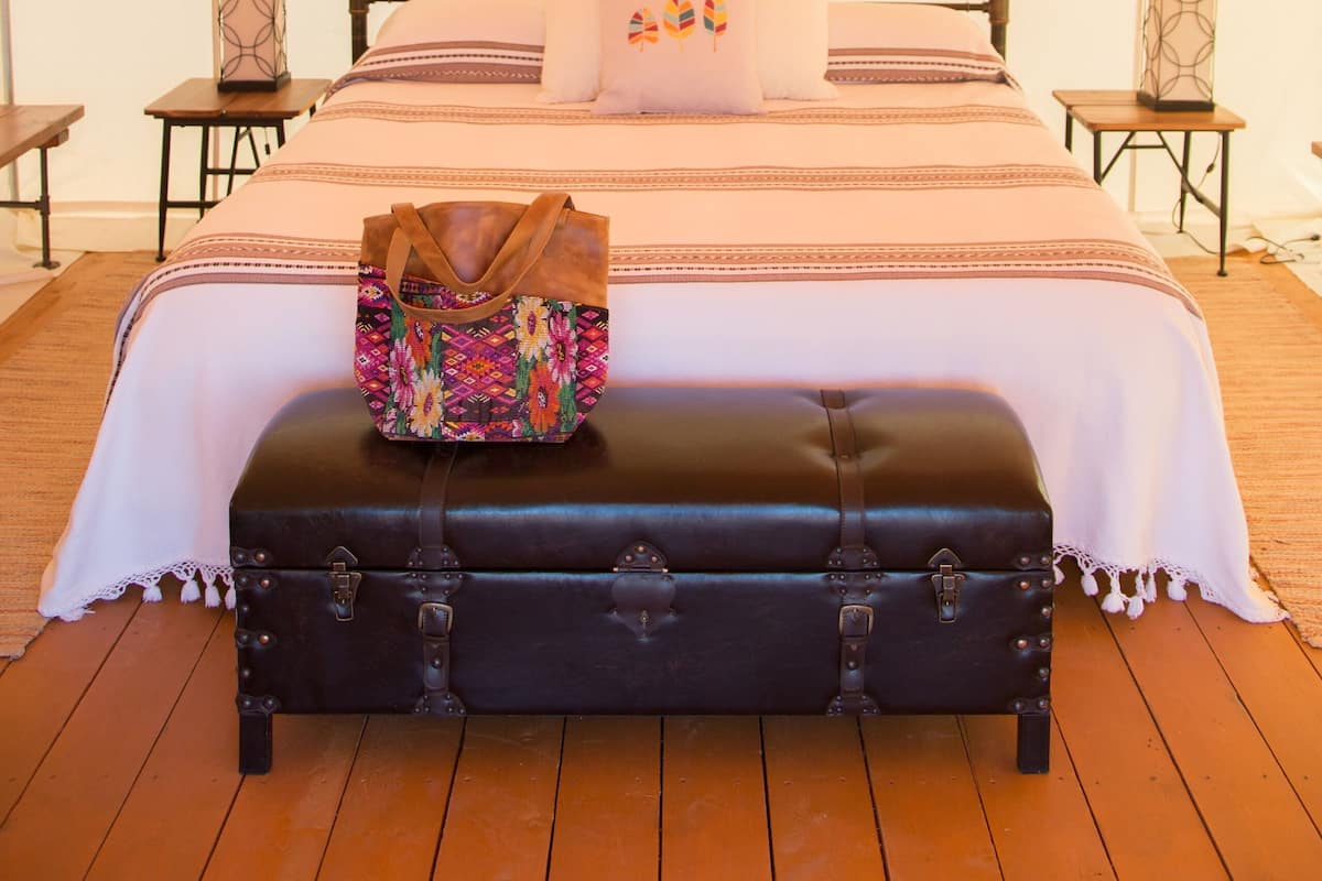 Quarto com tenda, uma cama, uma mala e uma bolsa.