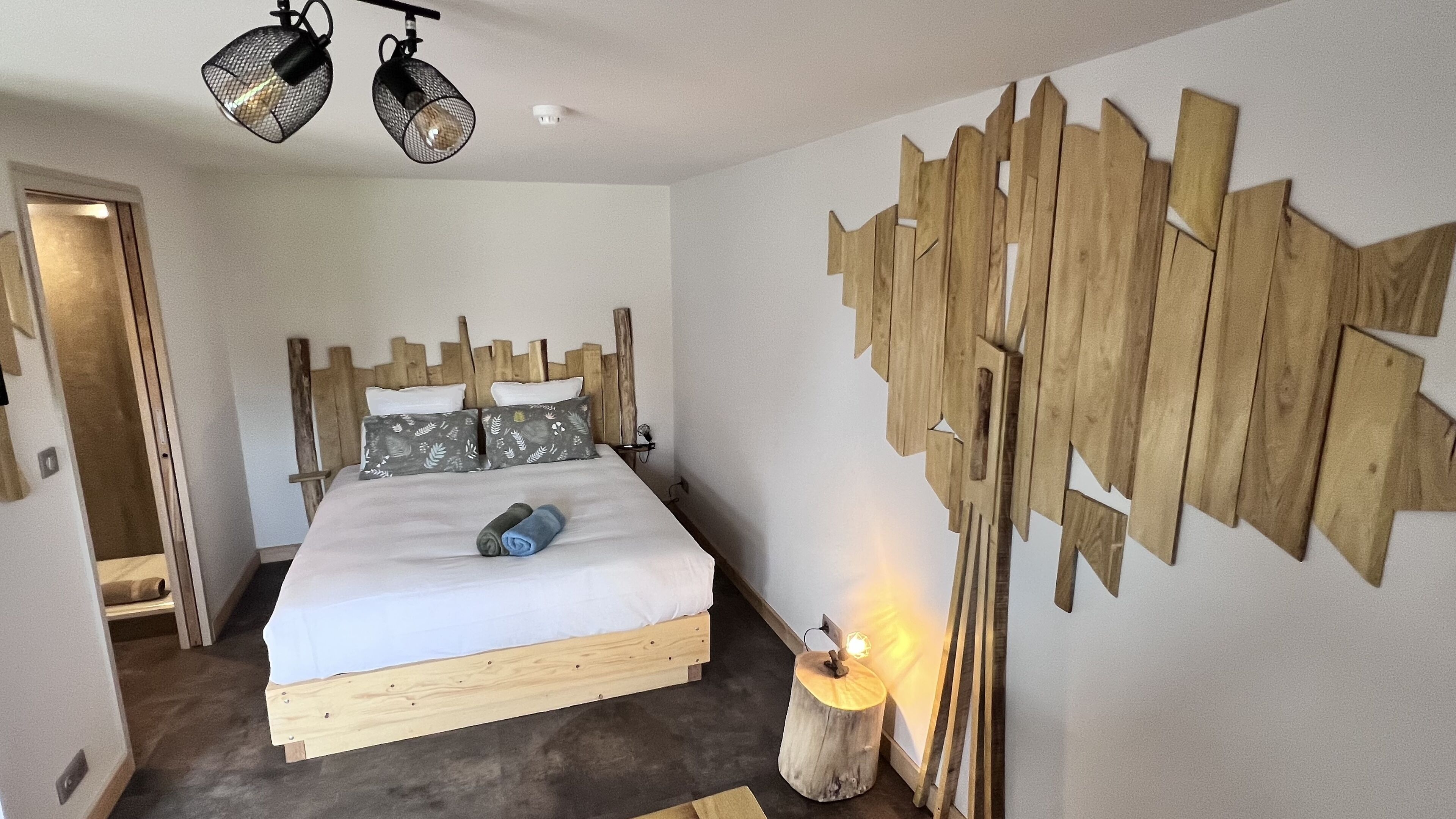 Quarto com estrutura de cama de madeira, cabeceira e uma obra de arte de madeira fixada na parede.