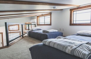 Quarto com duas camas, uma janela e vista para uma varanda.