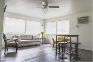 Sala de estar com sofá, cadeiras, mesa de centro e ventilador de teto.
