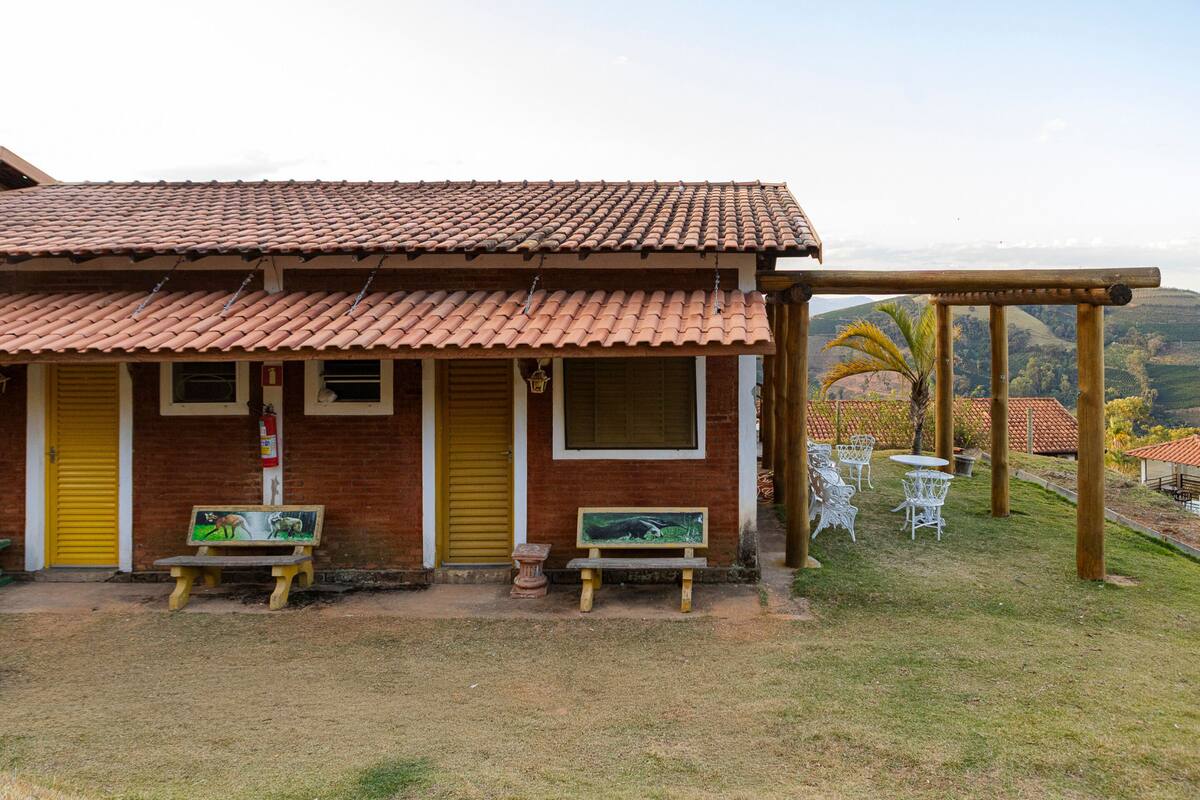 Um edifício com telhado de azulejos, um banco e uma mesa com cadeiras na parte externa.