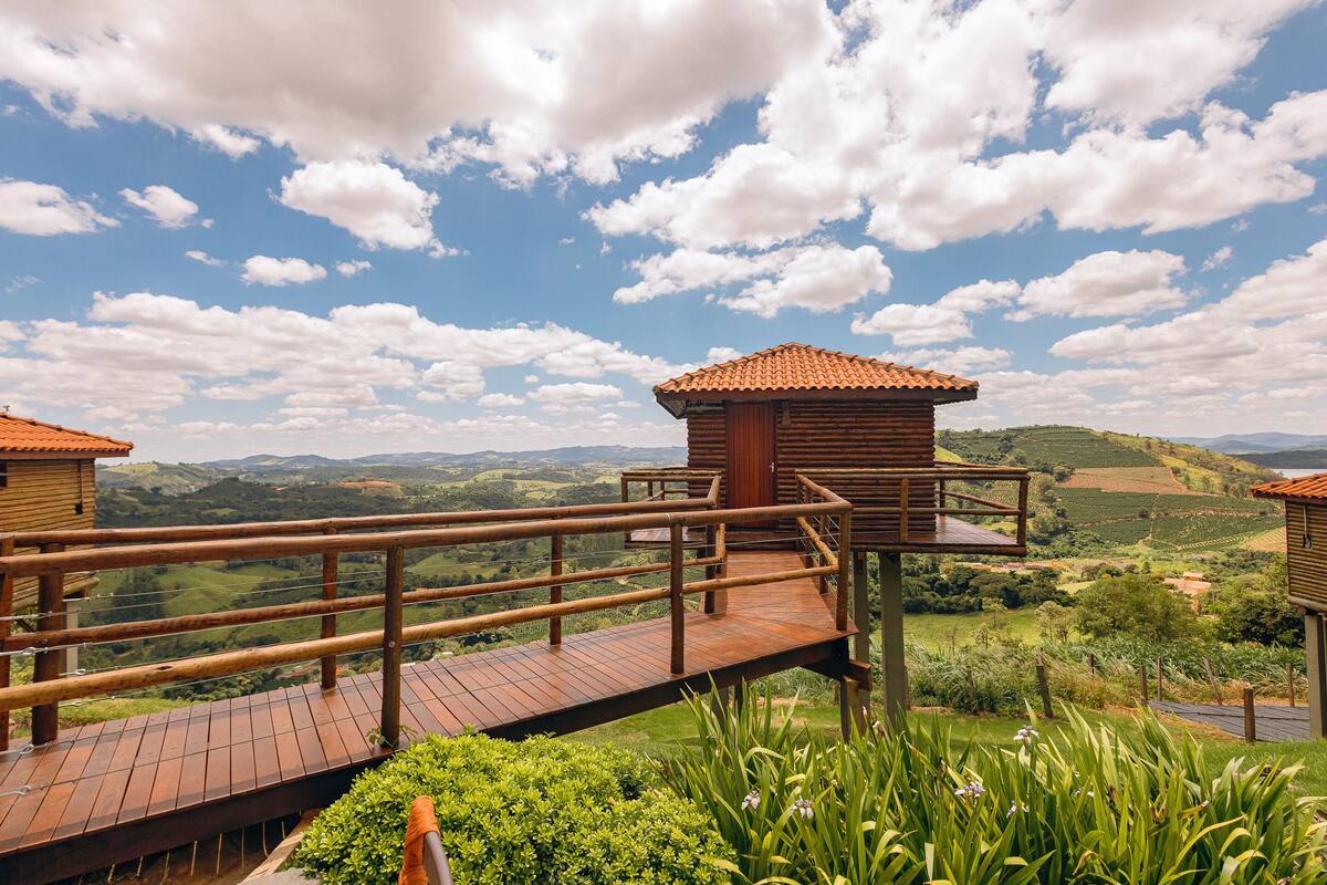 Um deck de madeira com guarda-corpo de madeira, com vista para um vale exuberante.