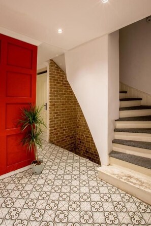 Uma escadaria com parede de tijolos e uma porta vermelha.