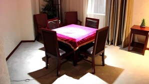 Uma área de jantar com uma mesa coberta por toalha rosa, rodeada por quatro cadeiras de madeira.