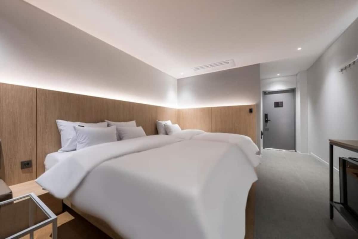 Quarto de hotel moderno com uma cama grande, uma mesa de cabeceira e uma pequena escrivaninha.