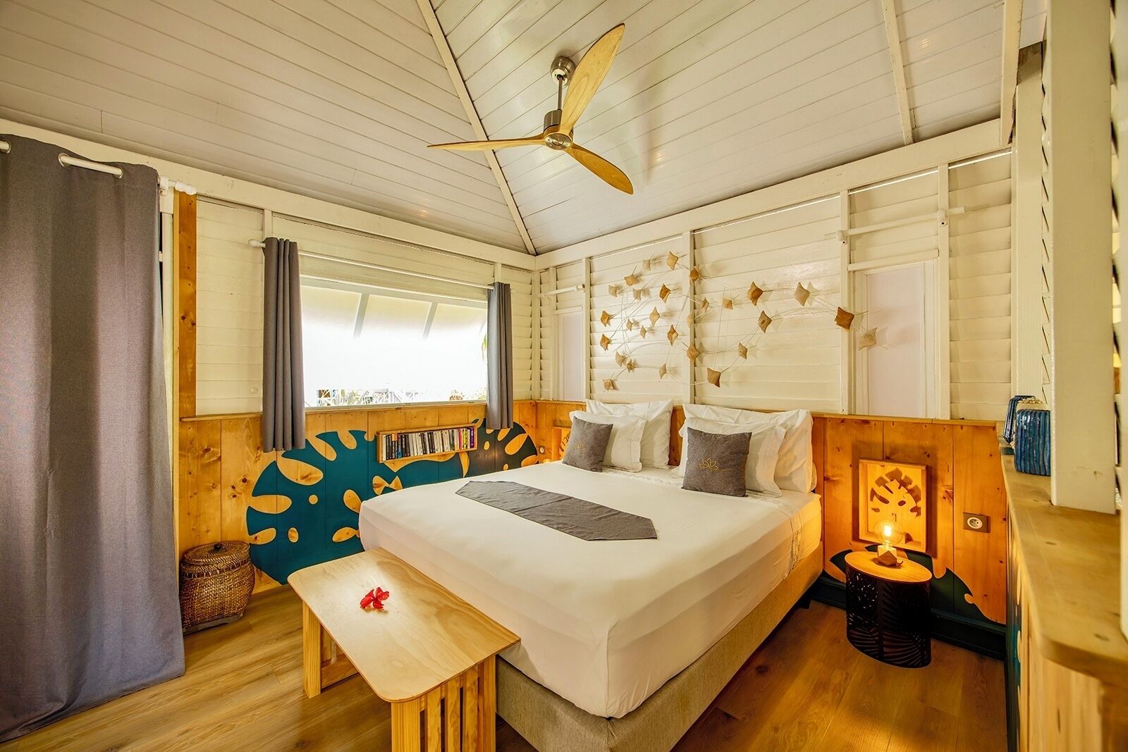 Um quarto espaçoso com uma cama grande, um ventilador de teto e vista para o exterior.