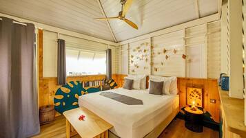 Um quarto espaçoso com uma cama grande, um ventilador de teto e vista para o exterior.