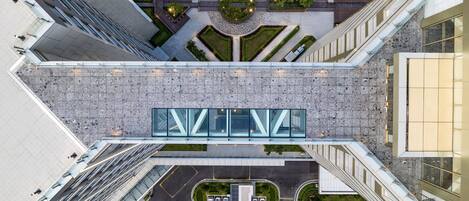 Um edifício moderno com fachada de vidro, um pátio central e uma área de estacionamento.