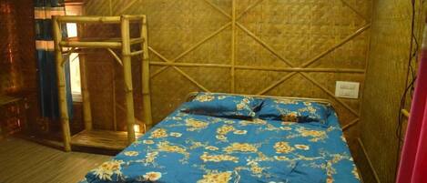 Quarto com cama, uma cadeira de madeira e estrutura de parede em bambu.