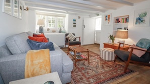 Uma sala de estar com sofá, poltronas, mesa de centro, tapete e estante de livros.