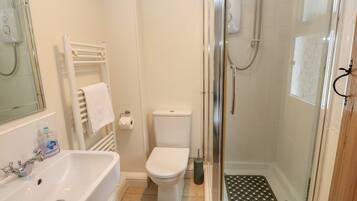 Casa de banho com lavatório branco, sanita e cabine de duche com vidro.