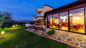 Uma casa moderna com um alpendre de pedra, área de estar ao ar livre e grandes janelas de vidro.