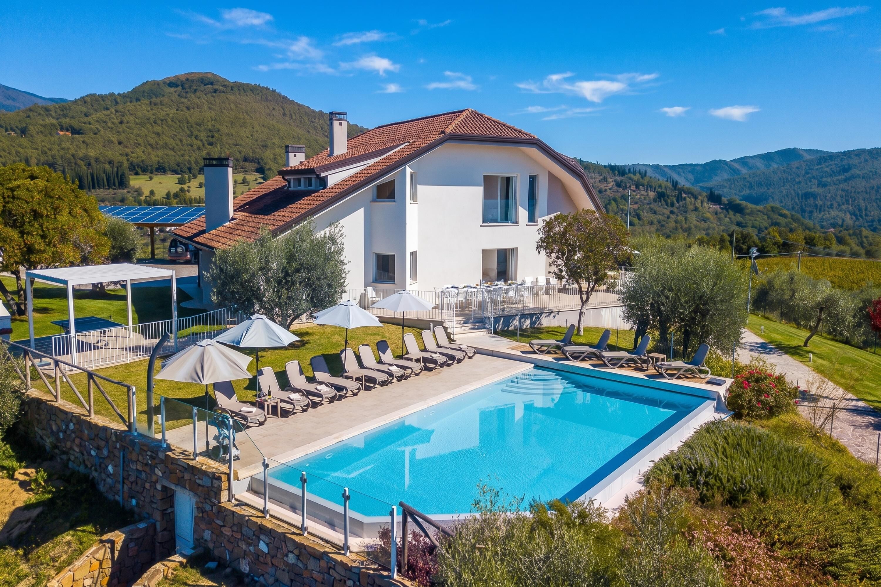 Uma casa moderna com piscina, área de estar ao ar livre e vista para as colinas ao redor.
