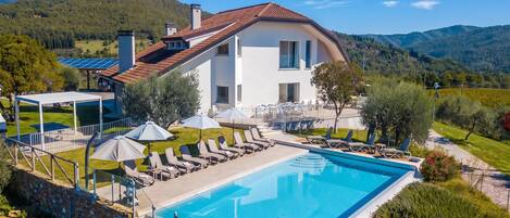 Uma casa moderna com piscina, área de estar ao ar livre e vista para as colinas ao redor.