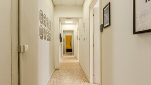 Um corredor com chão de azulejos, paredes brancas e portas em ambos os lados.