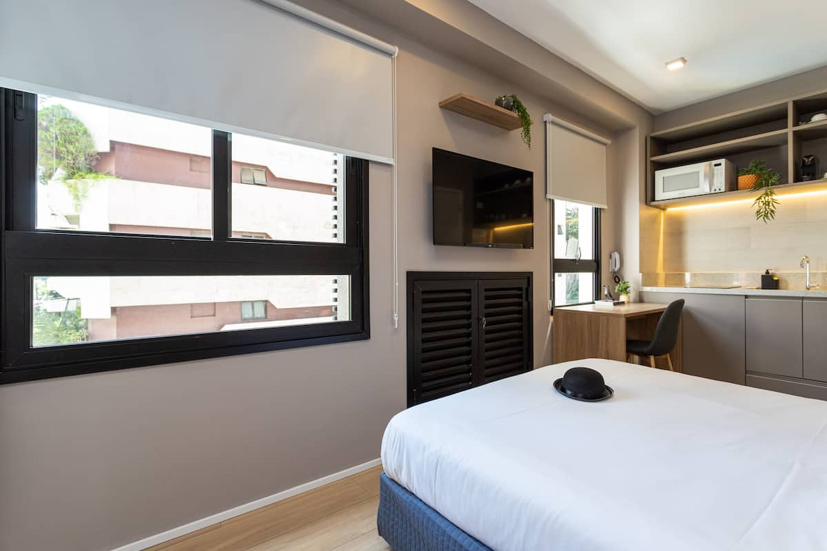 Quarto moderno com cama, escrivaninha e televisão.