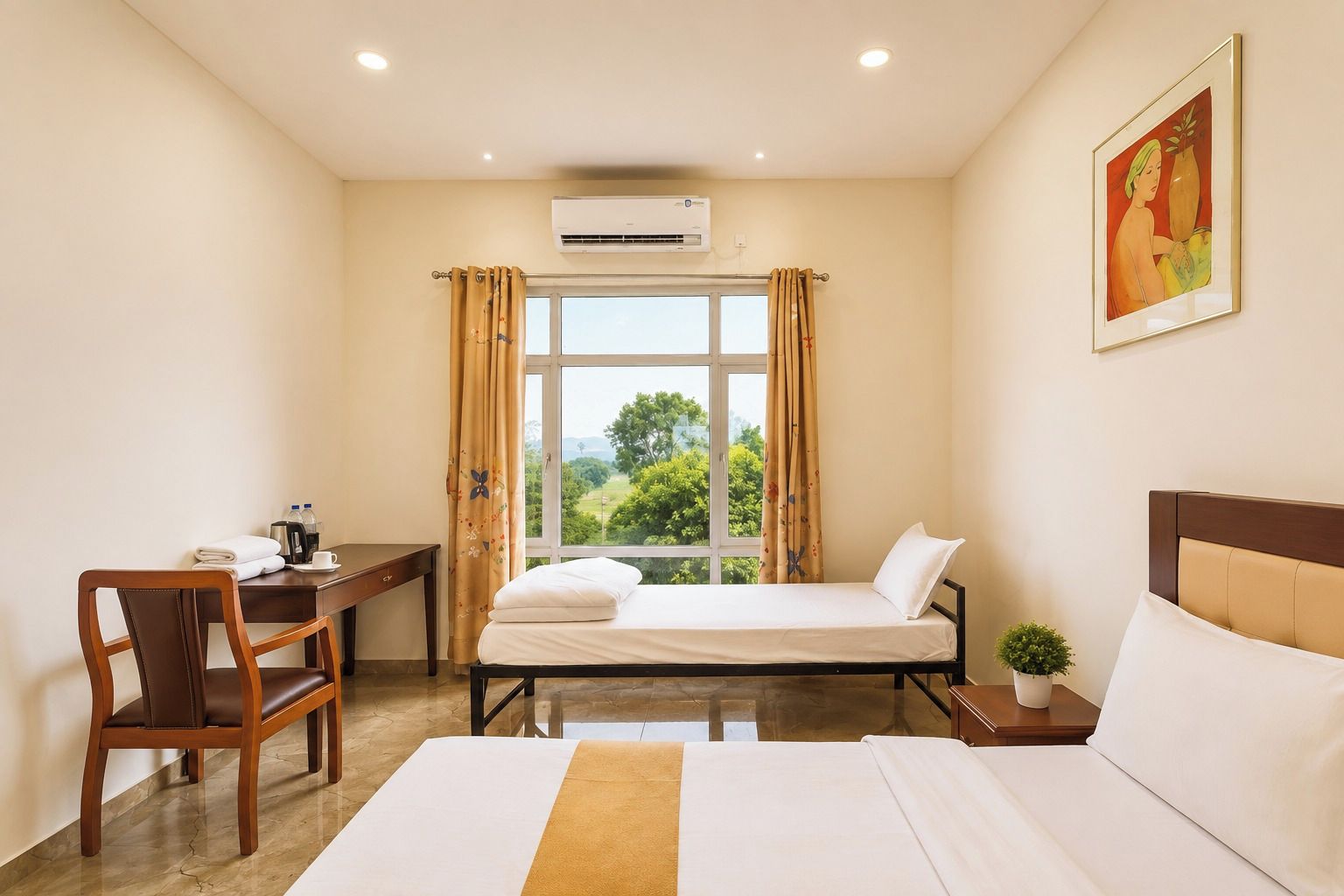 Quarto de hotel com cama, escrivaninha, cadeira, pequena mesa com uma planta e janela com cortinas.