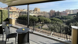 Varanda com mesa e cadeiras, vista para um horizonte urbano com edifícios e árvores.