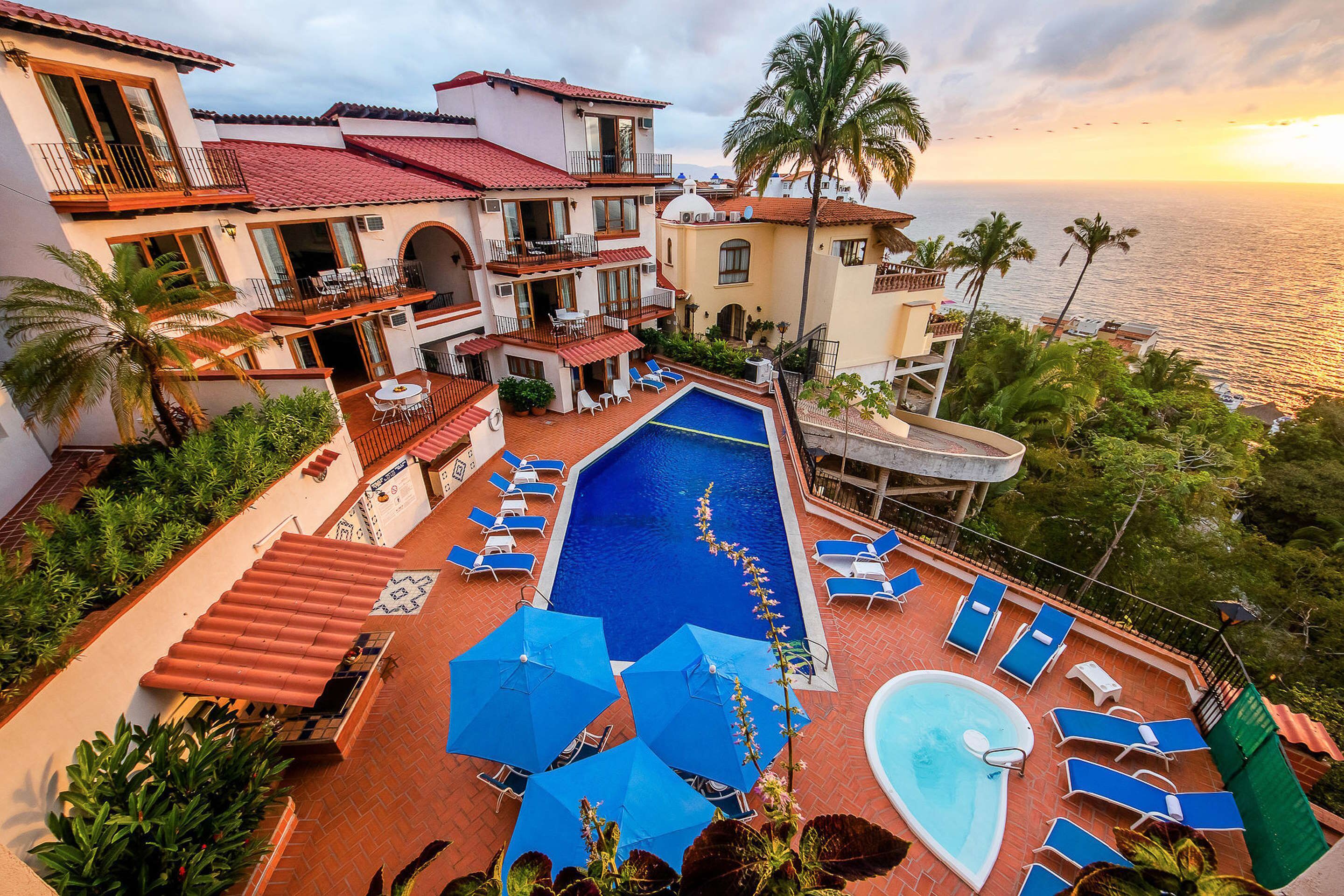 Um resort com piscina, espreguiçadeiras e vista para o oceano.