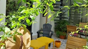 Uma área de pátio com mesa de madeira, cadeiras e um vaso de planta.