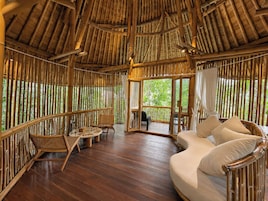 Quarto com teto de bambu, um sofá e uma área de refeições com cadeiras.