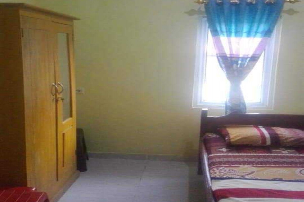 Quarto com cama, guarda-roupa e janela com cortinas.