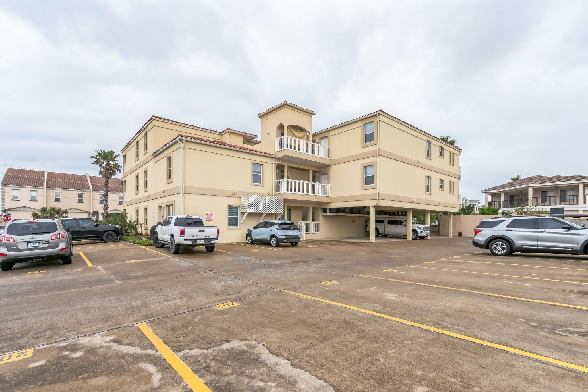 Um hotel com vários andares e um estacionamento em frente.
