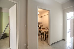 Corredor que dá para uma sala de jantar, com mesa e cadeiras.