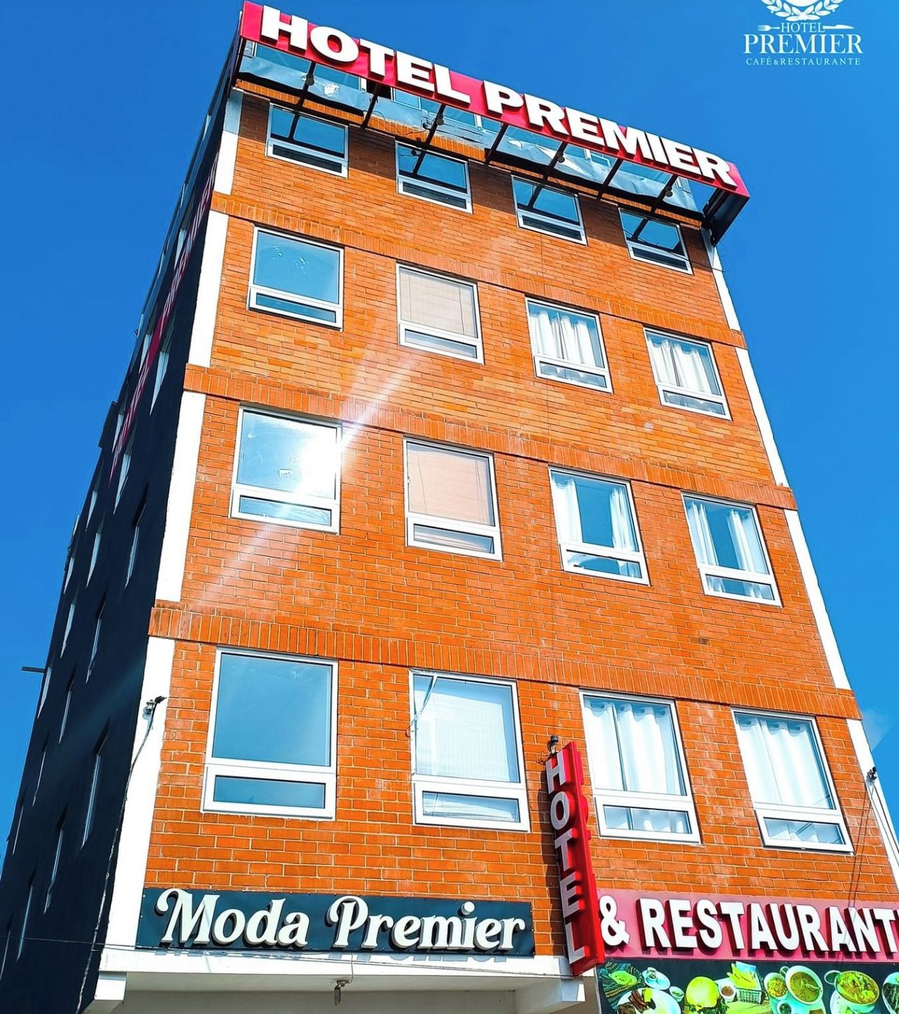 Um edifício de hotel com uma placa indicando "Hotel Premier" e "Moda Premier & Restaurant" na parte inferior.