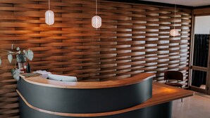 Uma receção moderna com design curvo, ripas de madeira na parede e iluminação pendente.