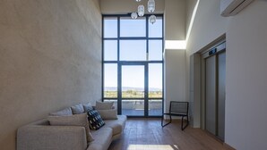 Uma sala de estar moderna com uma janela grande, um sofá e um banquinho.