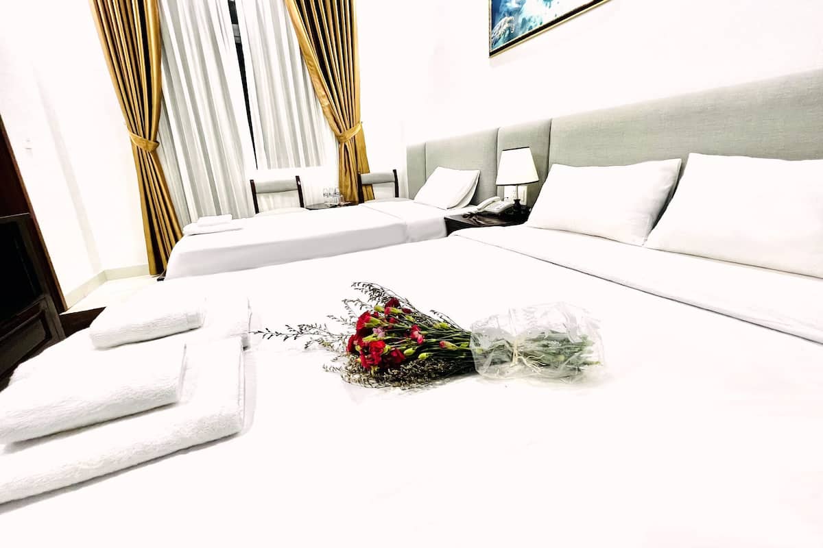 Quarto de hotel com uma cama, duas mesas de cabeceira, um abajur e um quadro na parede.
