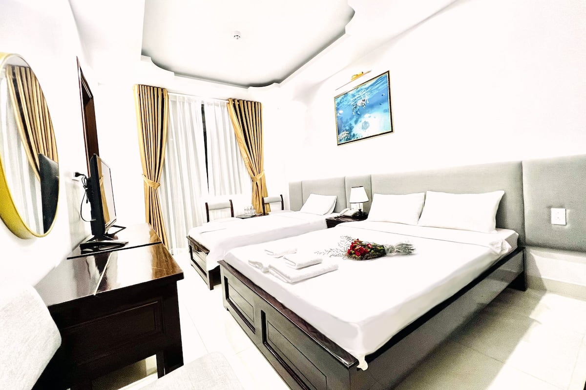 Quarto de hotel moderno com uma cama grande, mesas de cabeceira, uma escrivaninha e um espelho.